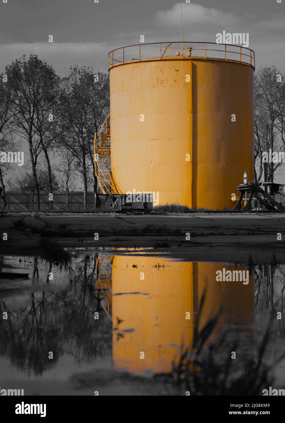 A grayscale shot of storage tanks for petroleum products with yellow ...