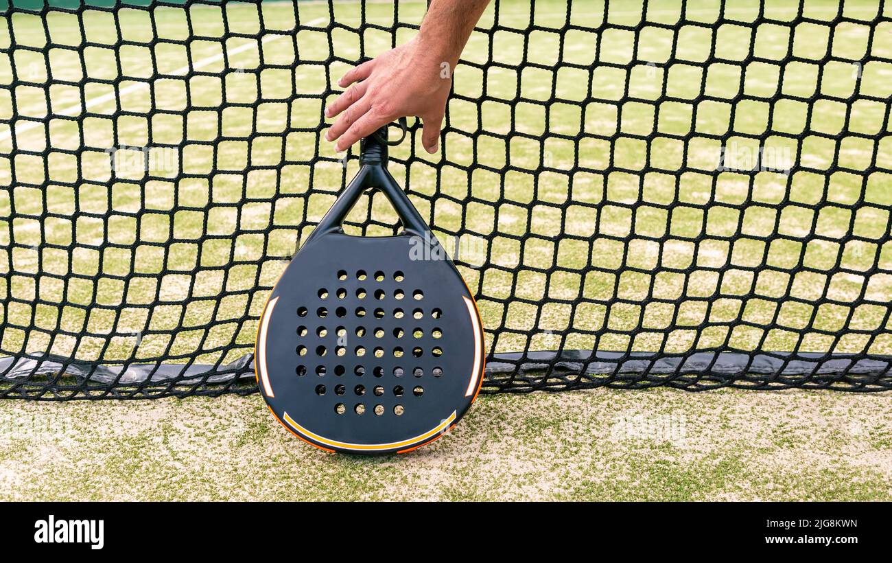 Professional monitor of padel holding a black racket behind the net ...