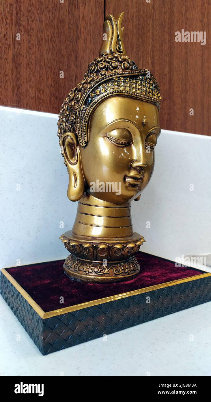 A vertical shot of a golden Lord Buddha brass statue with closed eyes ...