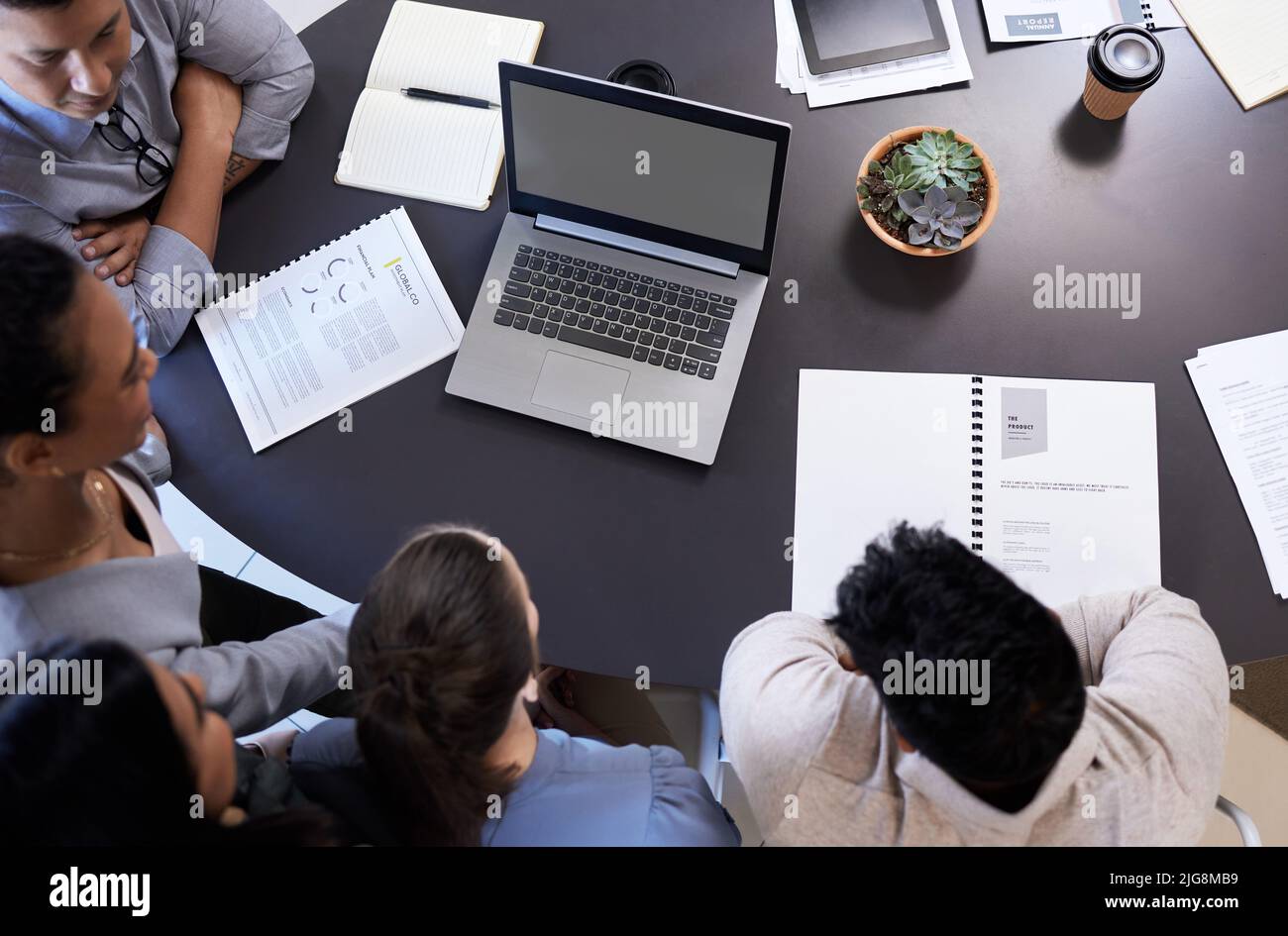 Giving it their best shot. Shot of an office table with staff using a ...