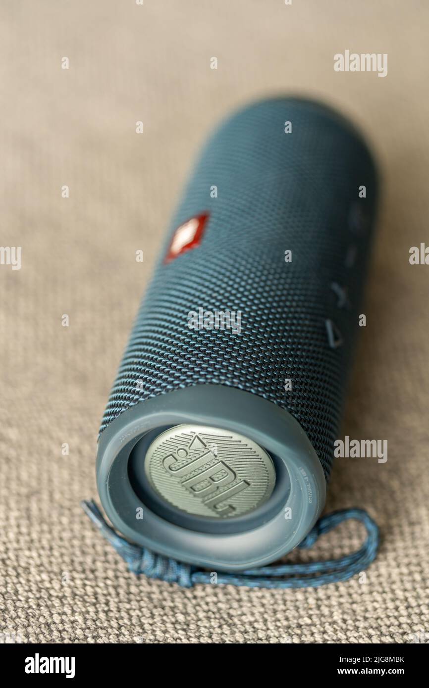 A vertical shot of the JBL brand music speaker laying on a fabric ...