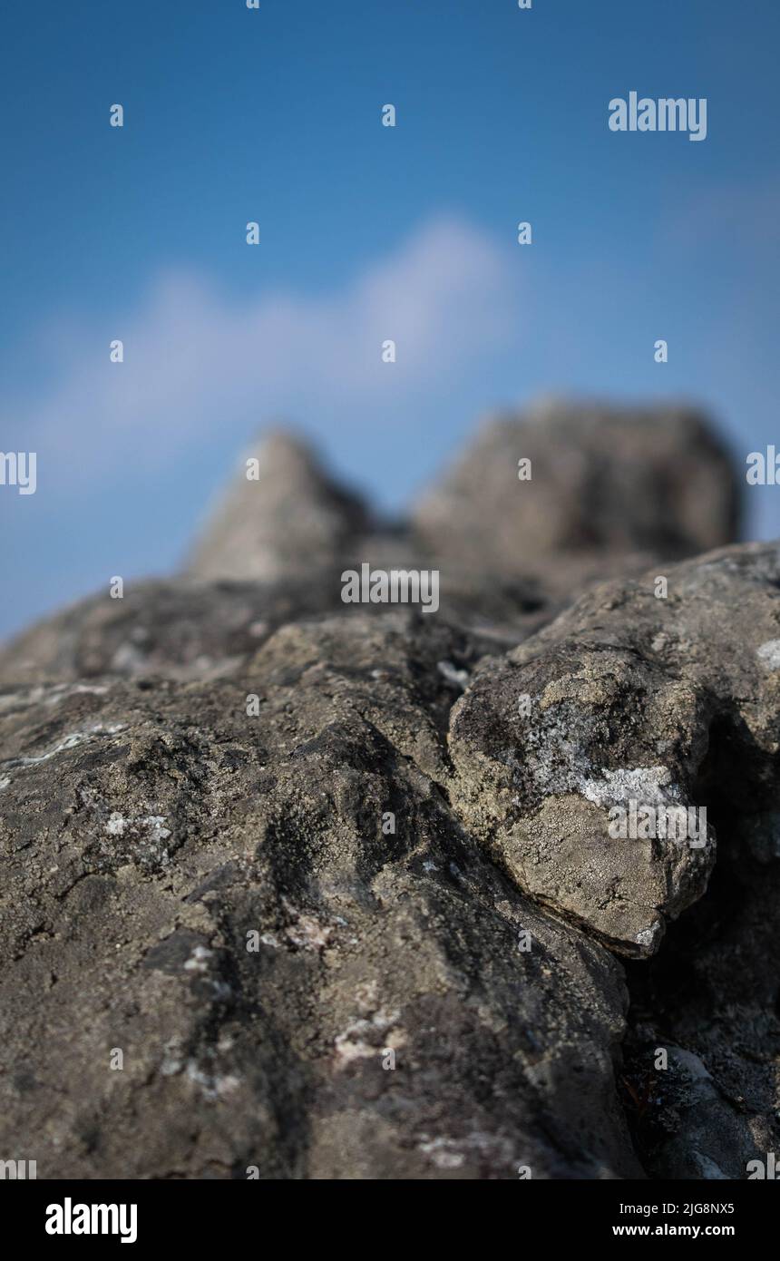 A vertical shot of a mossy stone on a blurry blue sky background Stock ...