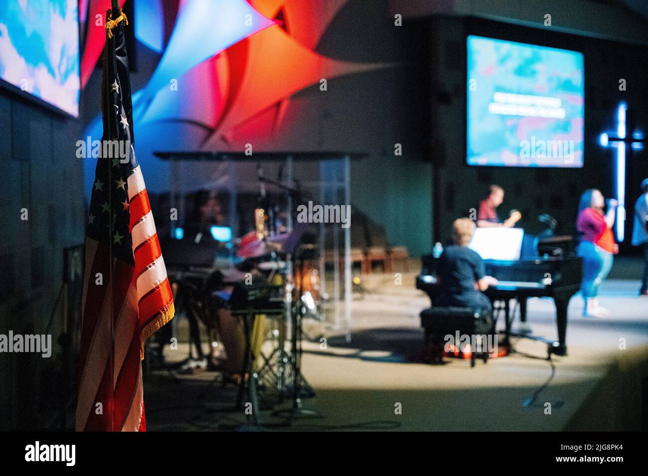 A flag of USA on a blurred stage background with people singing Stock ...