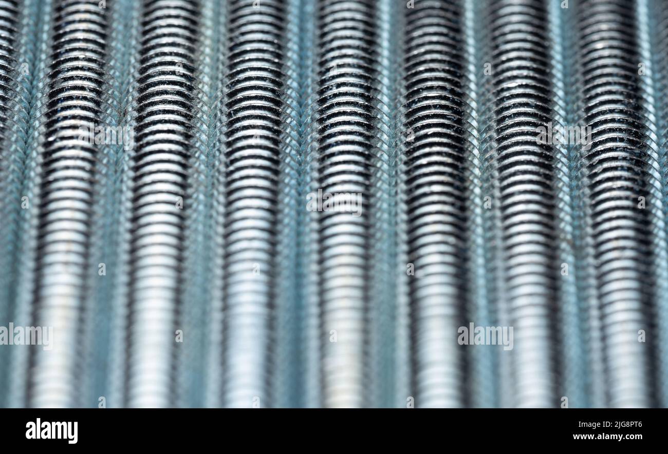 The threaded bolts are stacked side by side to create an abstract ...