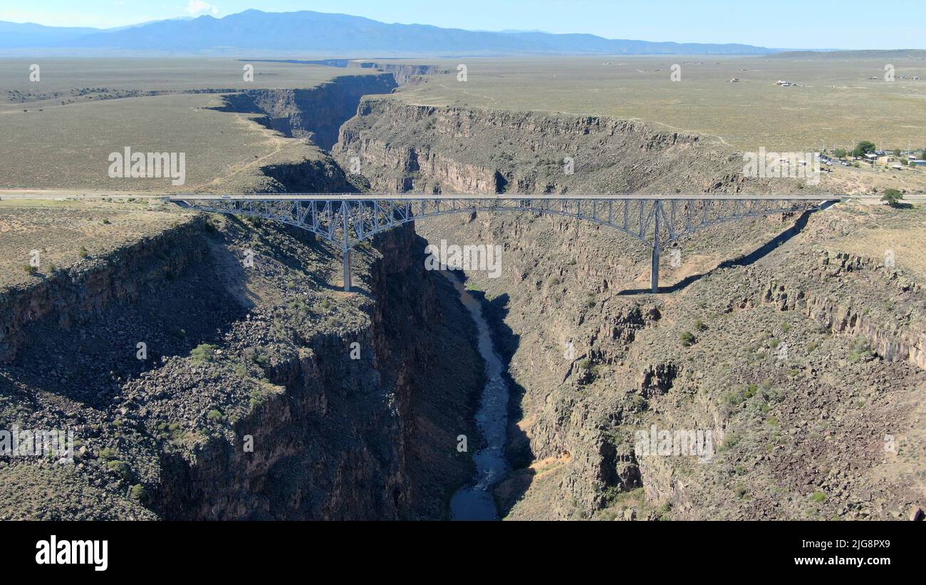 An aerial view of the Rio Grande Gorge Bridge over cliffs and a river ...