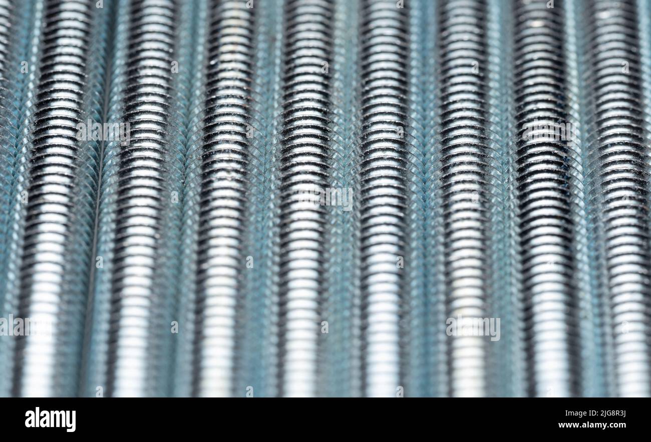 The threaded bolts are stacked side by side to create an abstract ...