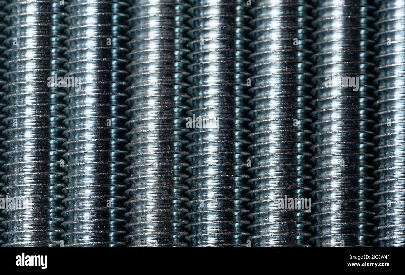 The threaded bolts are stacked side by side to create an abstract ...