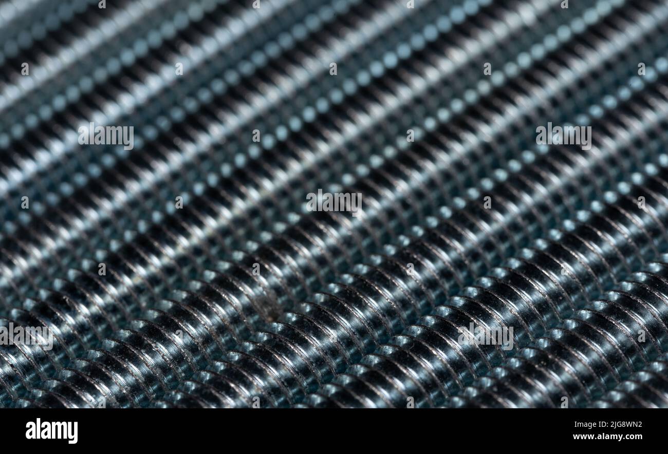 The threaded bolts are stacked side by side to create an abstract ...