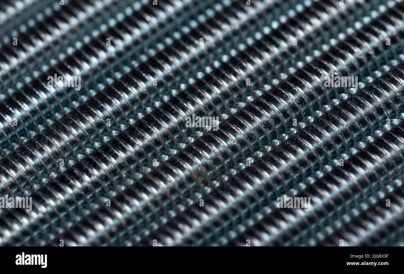 The threaded bolts are stacked side by side to create an abstract ...