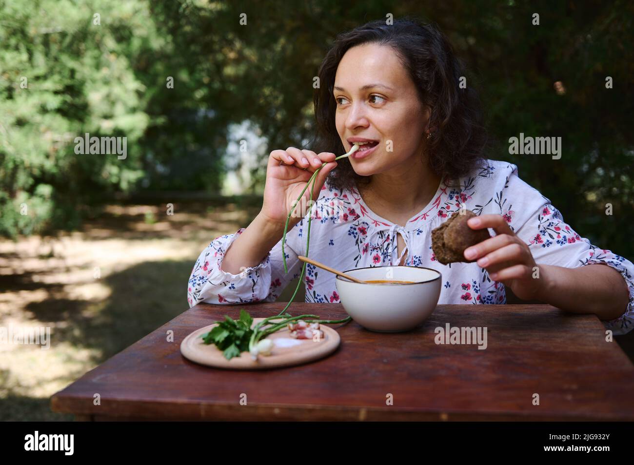 Charming woman sits at rustic dining table, tastes Ukrainian national ...
