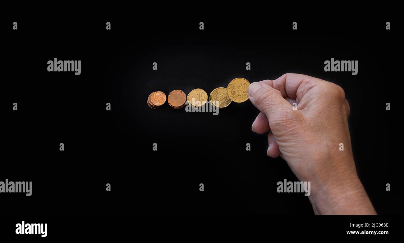 close-up, the hand of an elderly woman lays out coins on a black ...