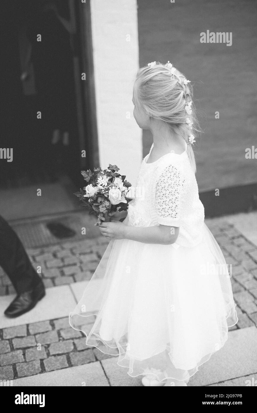 A grayscale back view of young beautiful flower girl of the wedding ...
