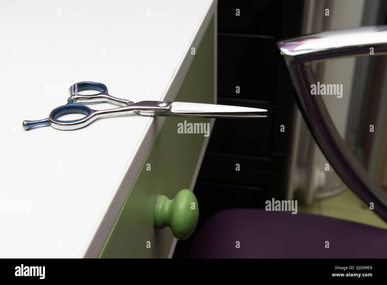 Stainless steel scissors and a black barber comb on a large white ...