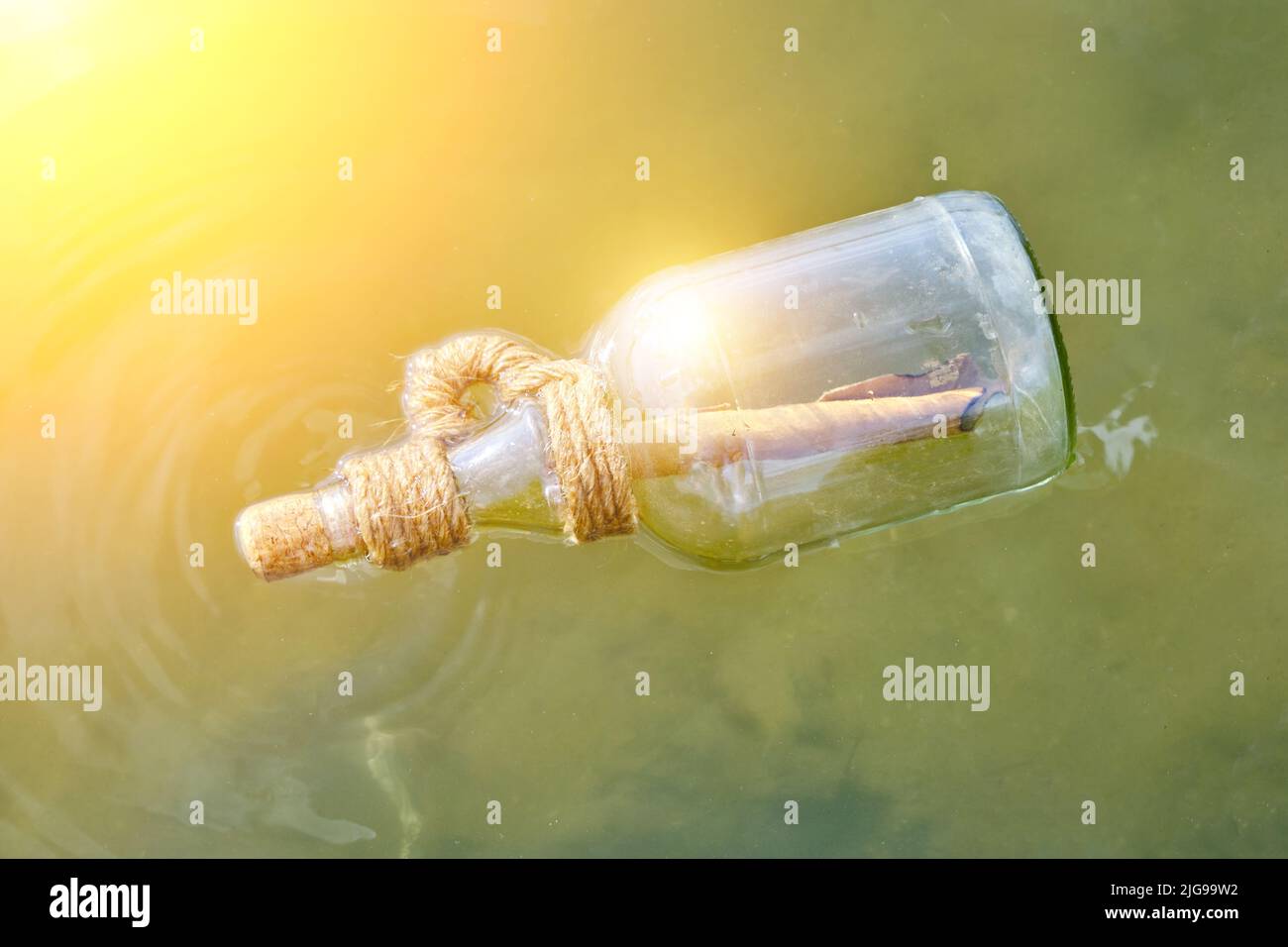 Bottle floating on water with a rolled letter inside.Message call for ...