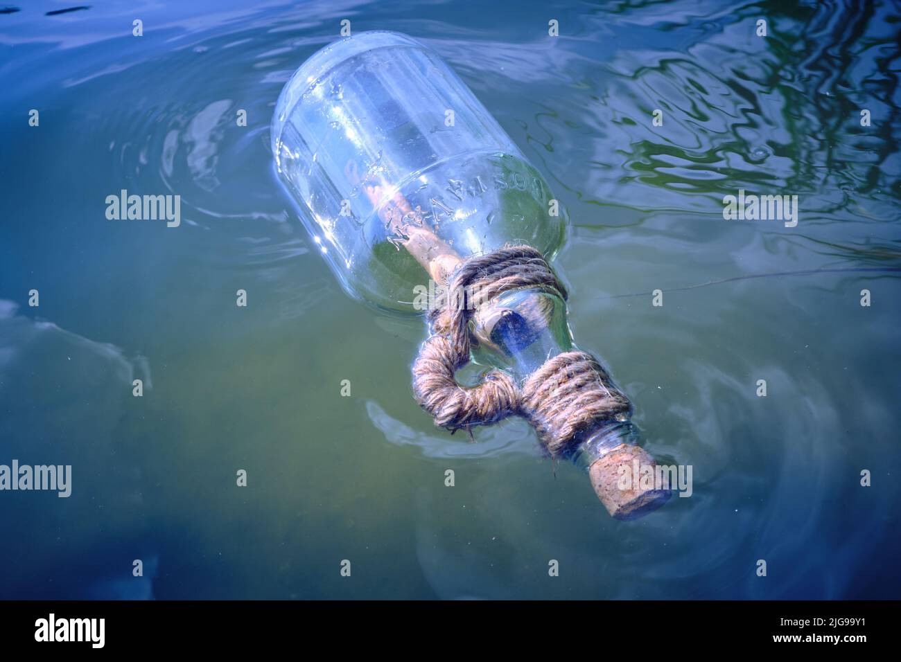 Bottle floating on water with a rolled letter inside.Message call for ...