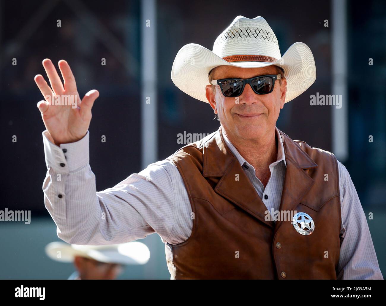 Parade marshal Kevin Costner, centre, waves to fans during the Calgary ...
