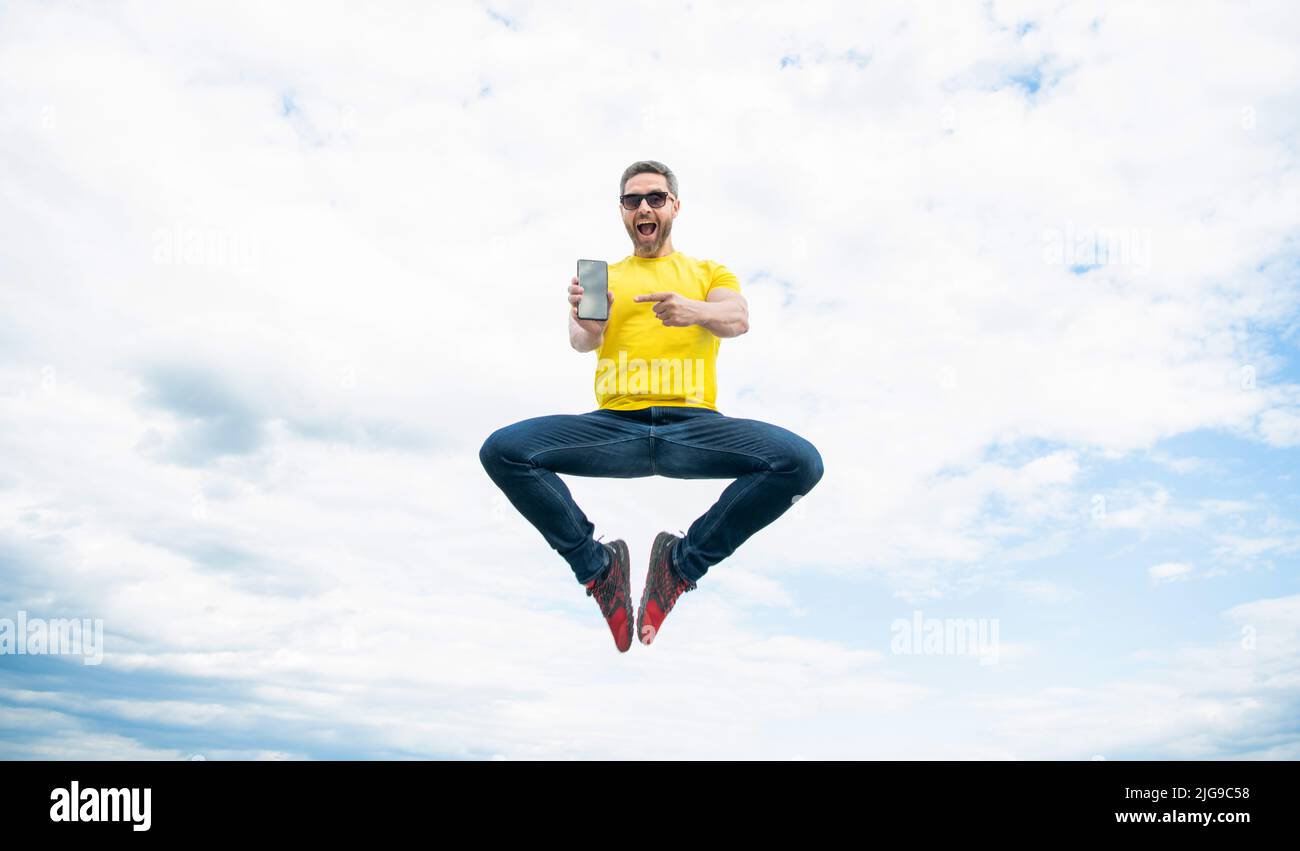 amazed man jumping and presenting smartphone on sky background Stock ...