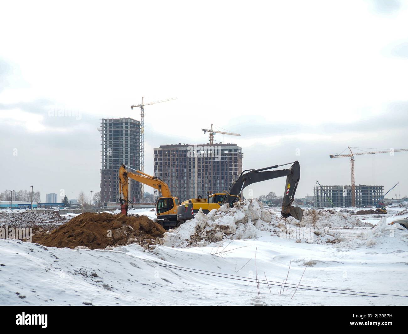 Construction of high-rise buildings in winter. The work of excavators ...