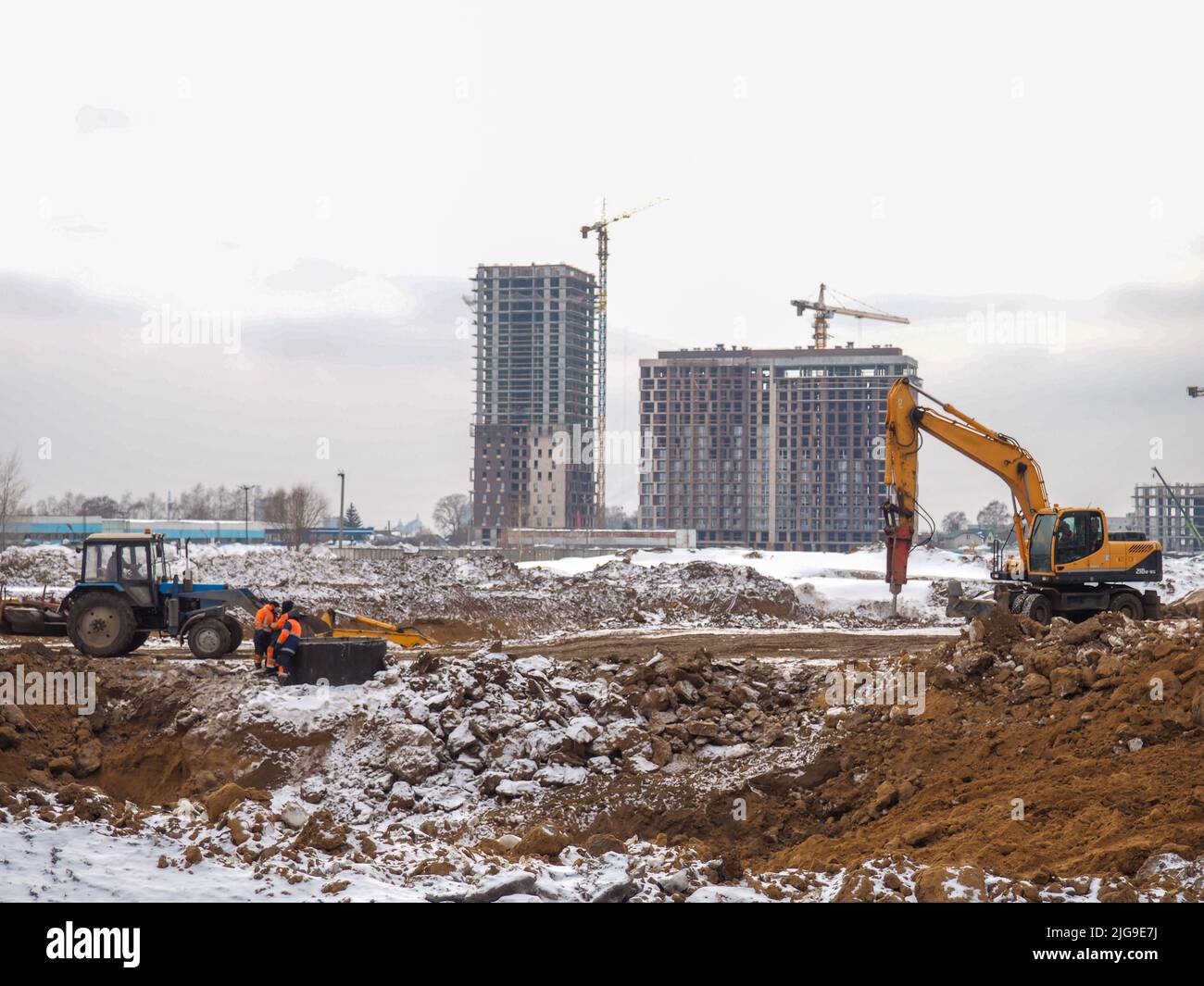 Construction of high-rise buildings in winter. The work of excavators ...