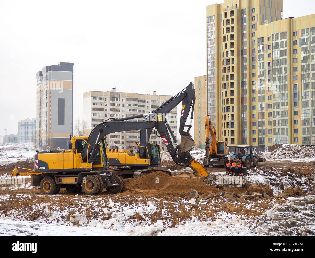 Construction of high-rise buildings in winter. The work of excavators ...
