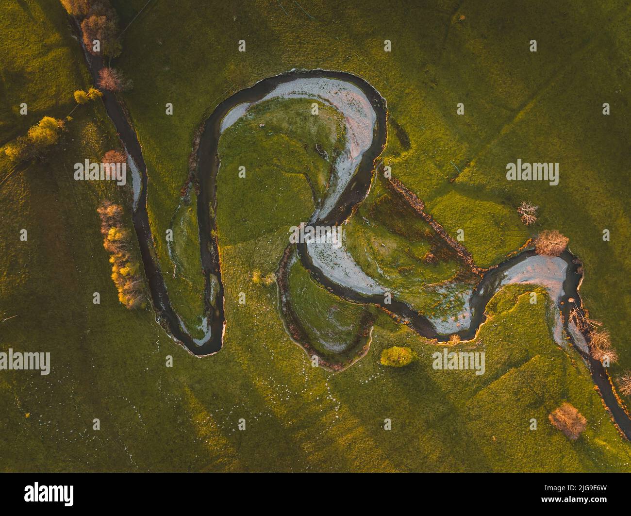An aerial view of a weaving river flowing through the green field in ...