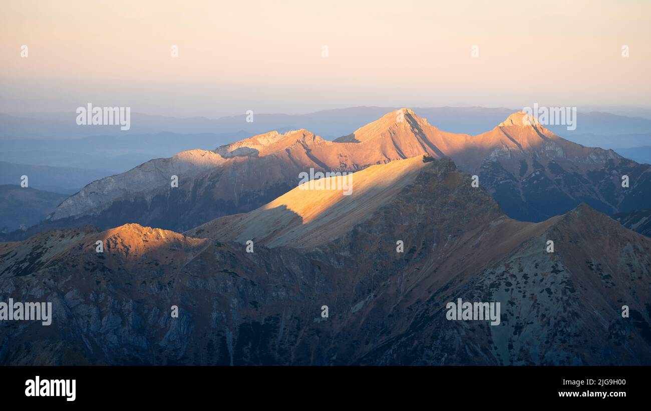 Alpine landscape with mountain ranges, peaks catching last light during ...