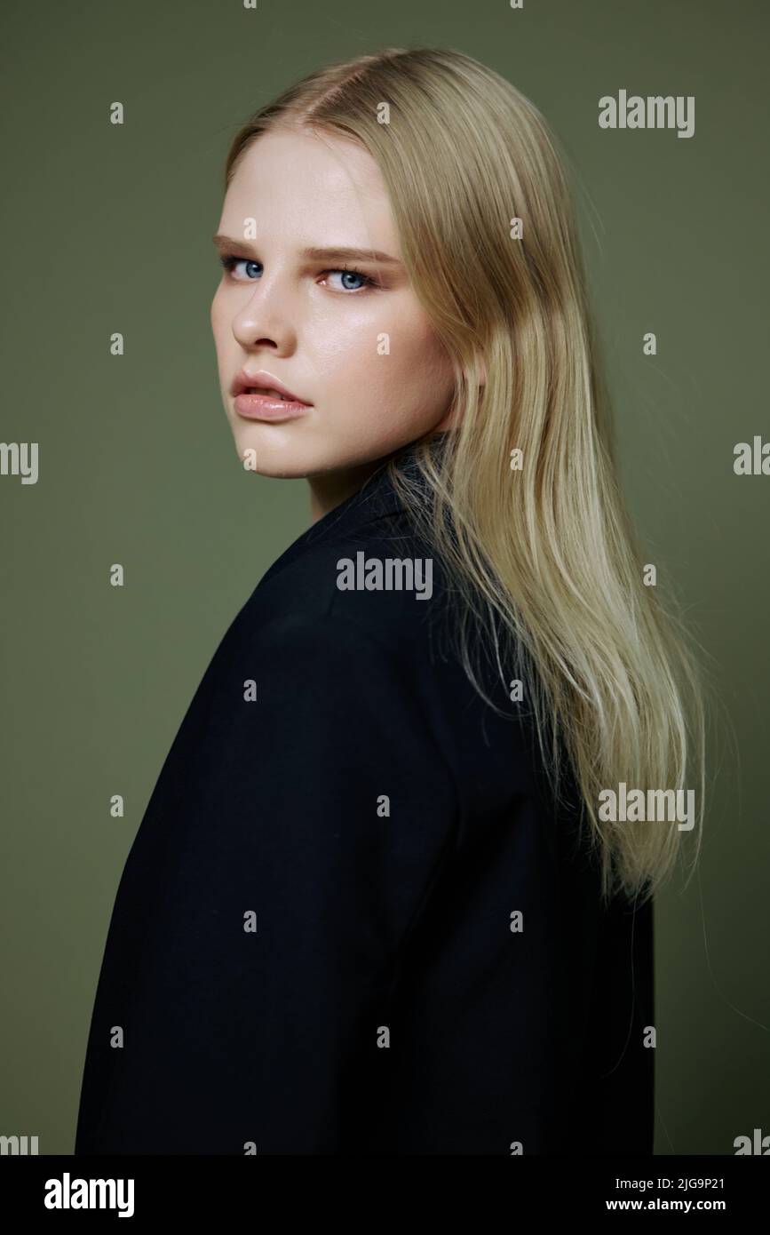 A beautiful girl looks half-turned into the camera at you posing on a ...