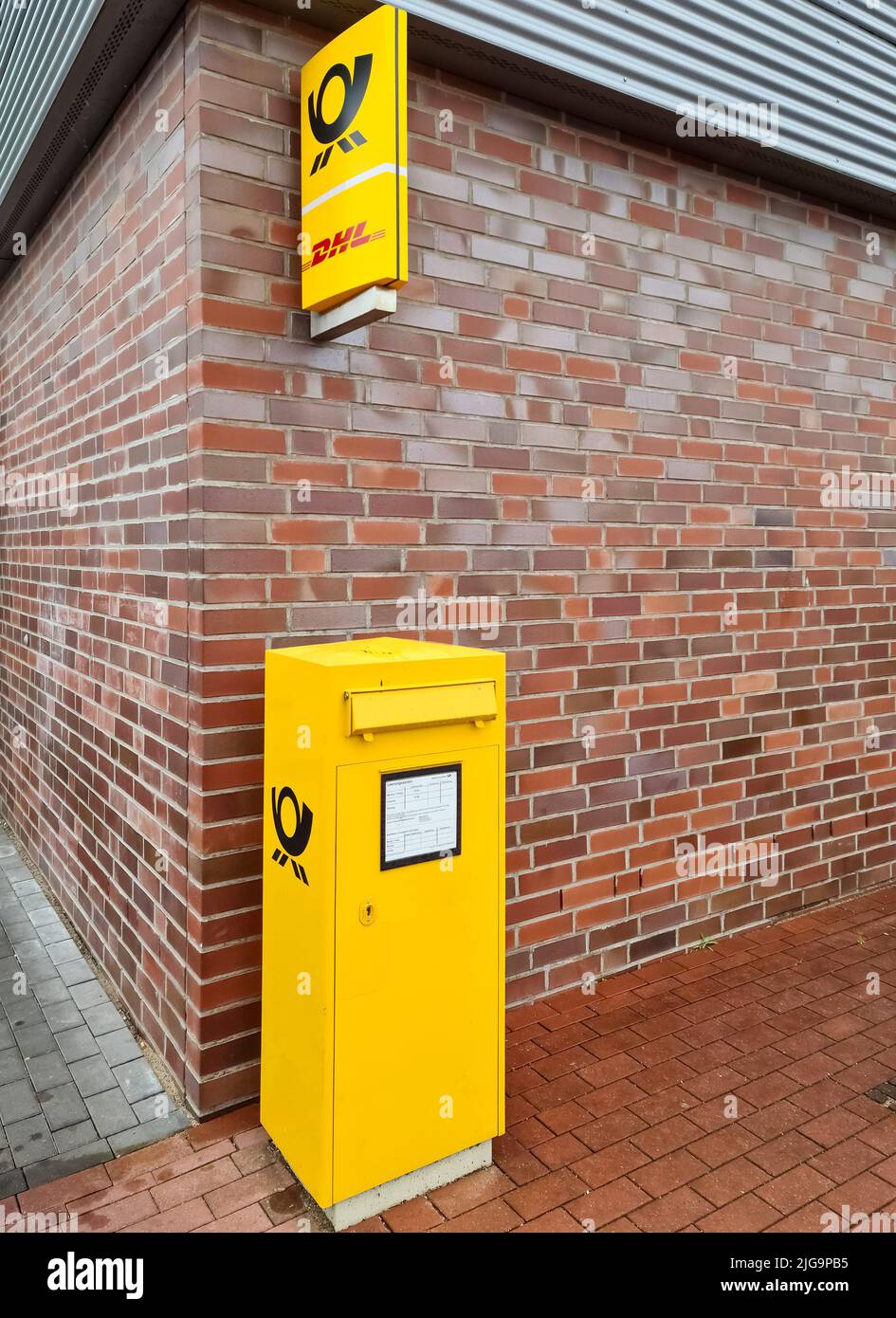 Kiel, Germany - 07. July 2022. A yellow german postbox at a red brick ...
