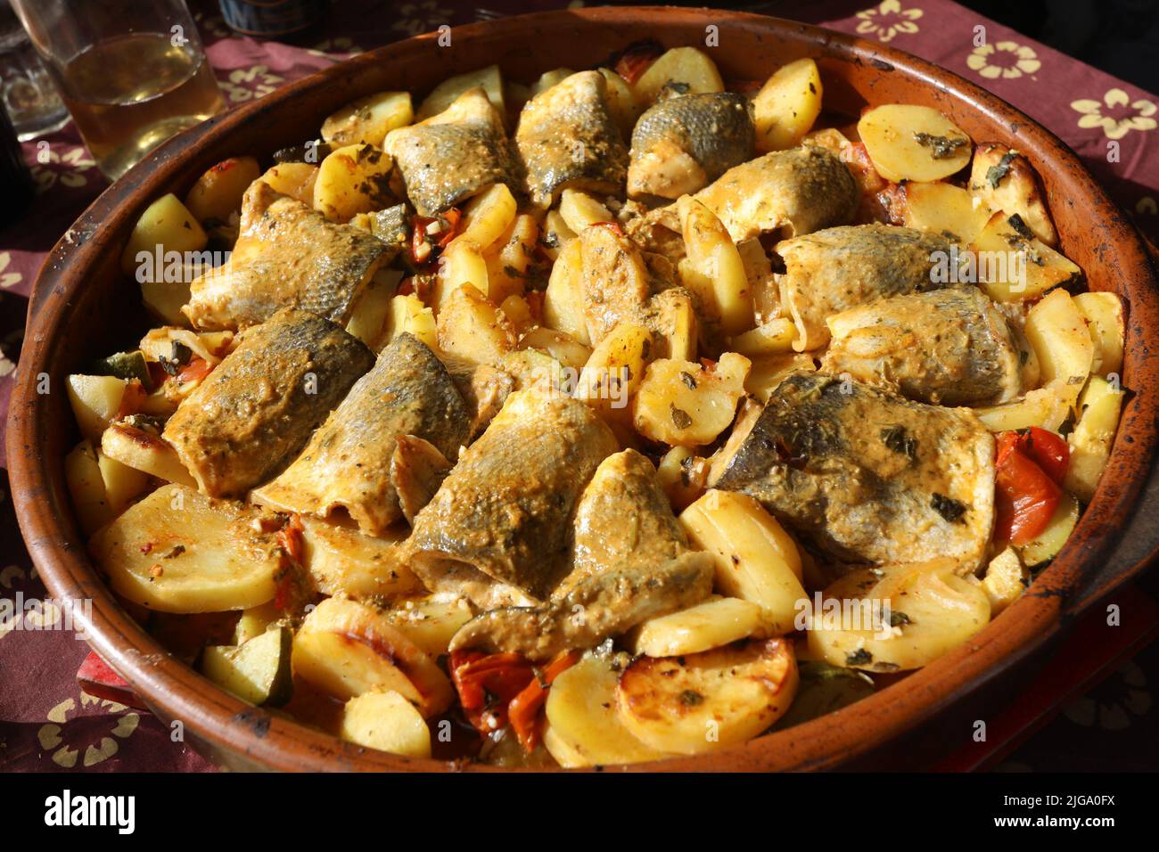 Lubinia fish cooked at the oven with potatoes, onion Stock Photo - Alamy