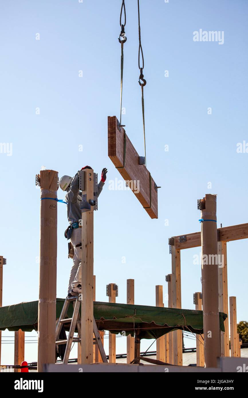 Construction worker guides beam at building site in Ikegami, Tokyo ...
