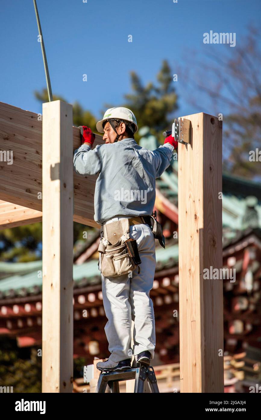 Construction worker guides beam at building site in Ikegami, Tokyo ...