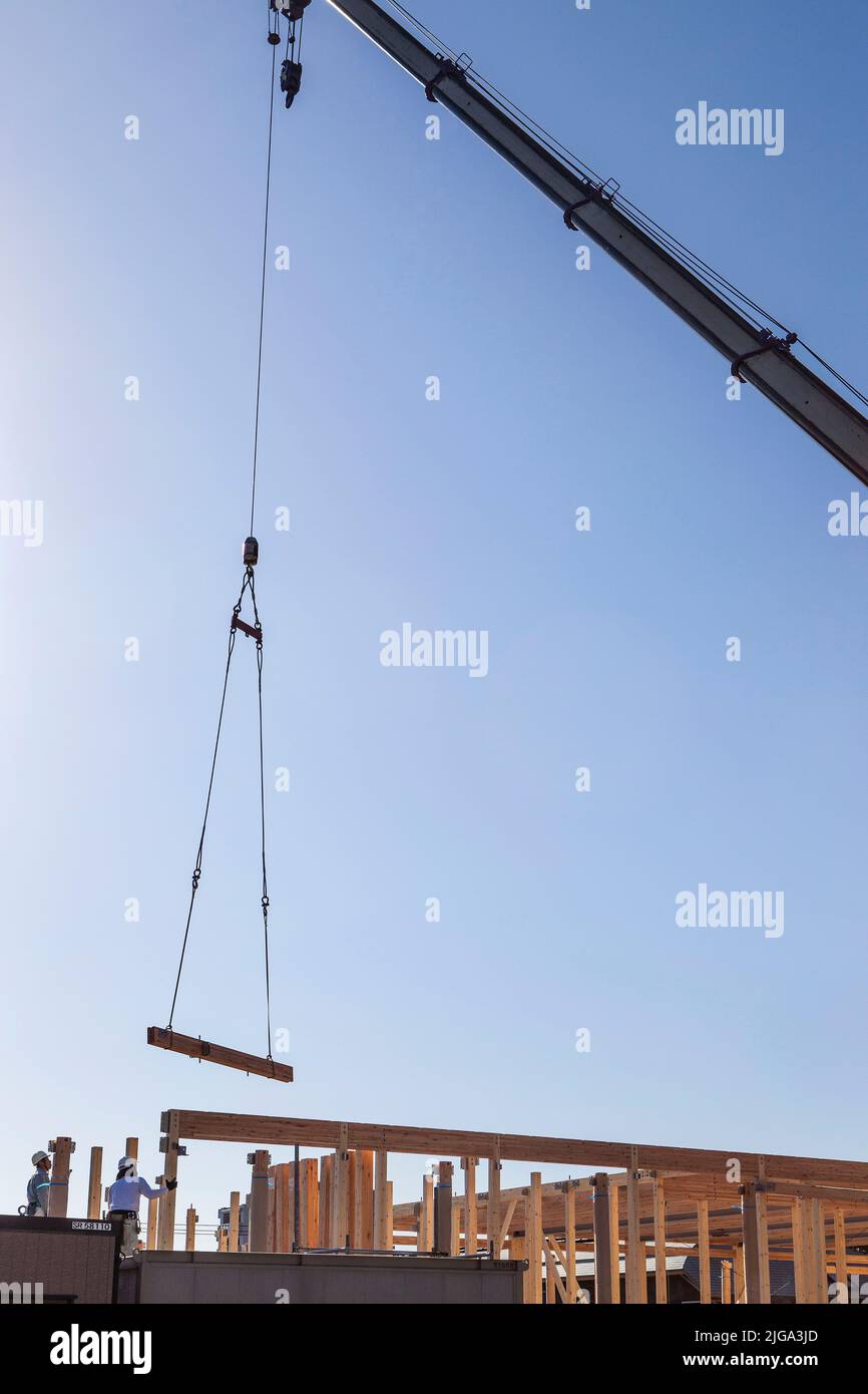 Construction workers guide beam at building site, Ikegami, Tokyo, Japan ...