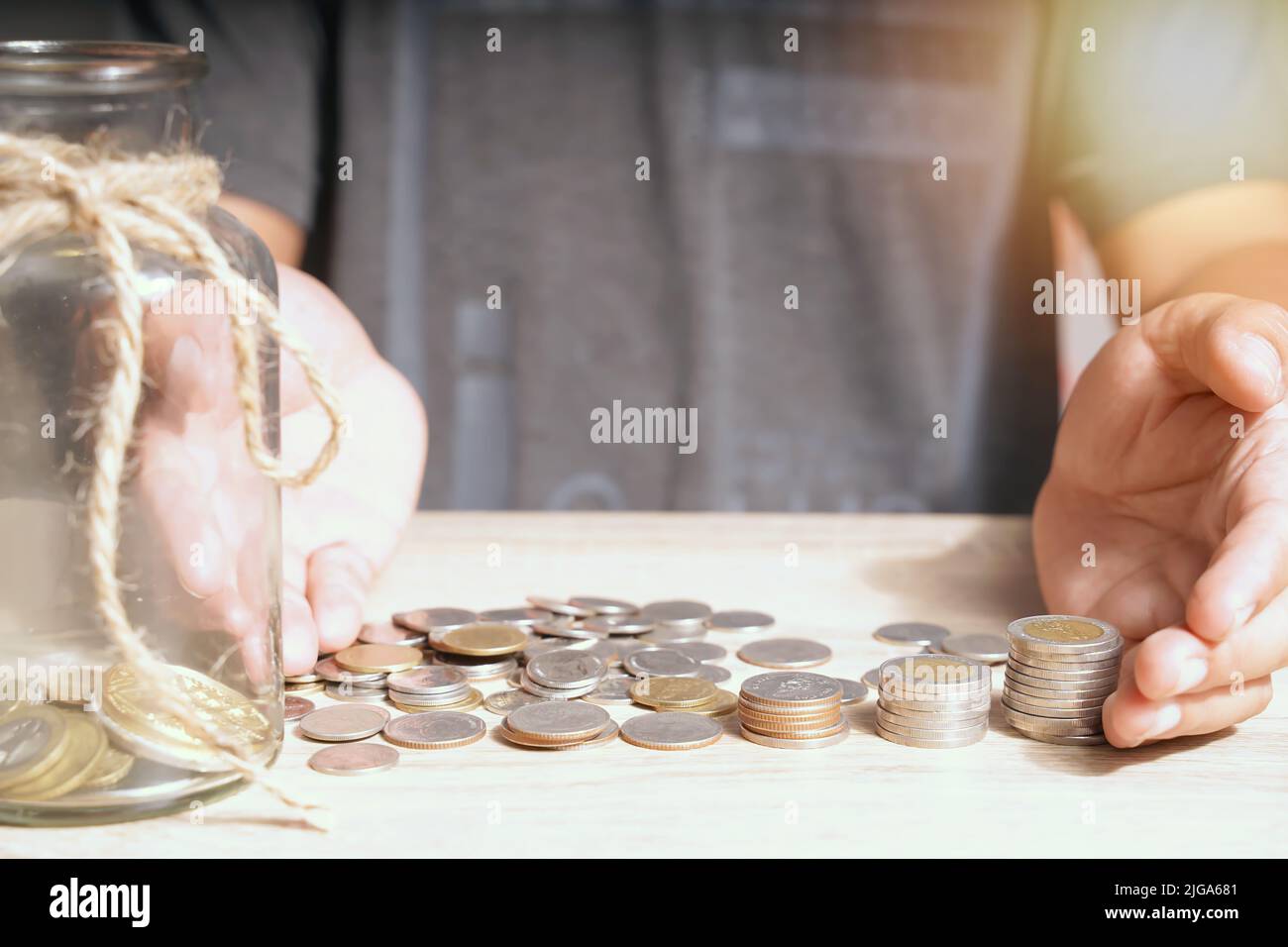 Man's hand scooping up stacked coins with curves showing monetary ...