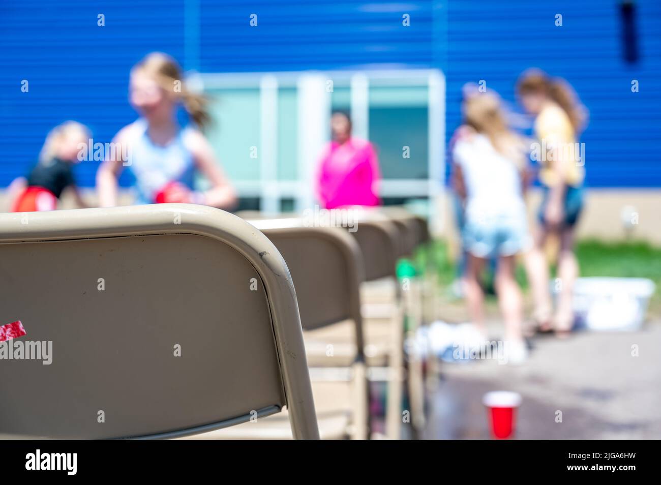 Selective focus on rows of metal folding chairs at an outdoor school ...