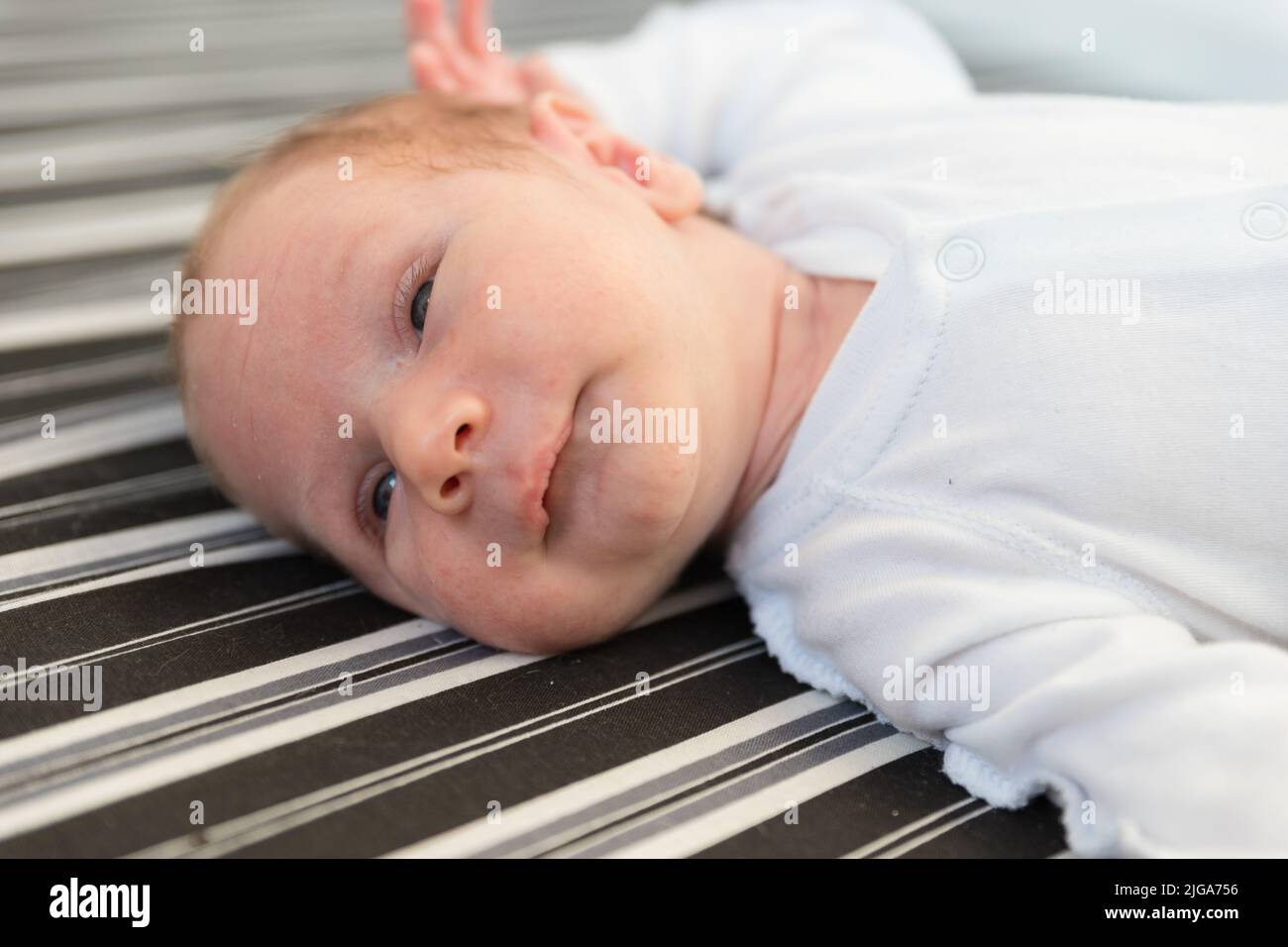 Face of a newborn baby lying on his back on striped sheet Stock Photo ...