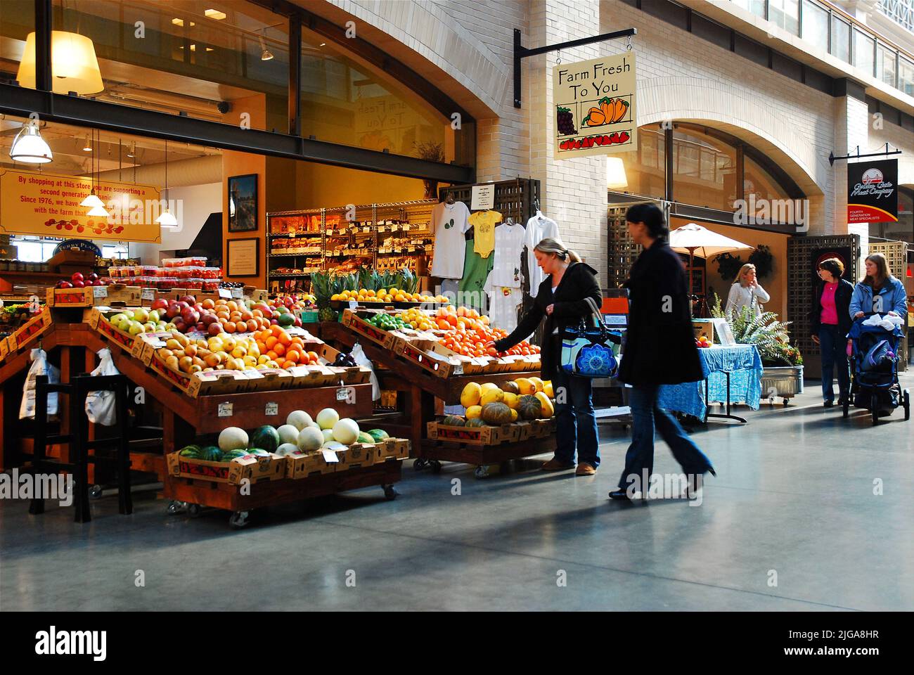 Customers shop at an organic food store with a display of locally grown ...