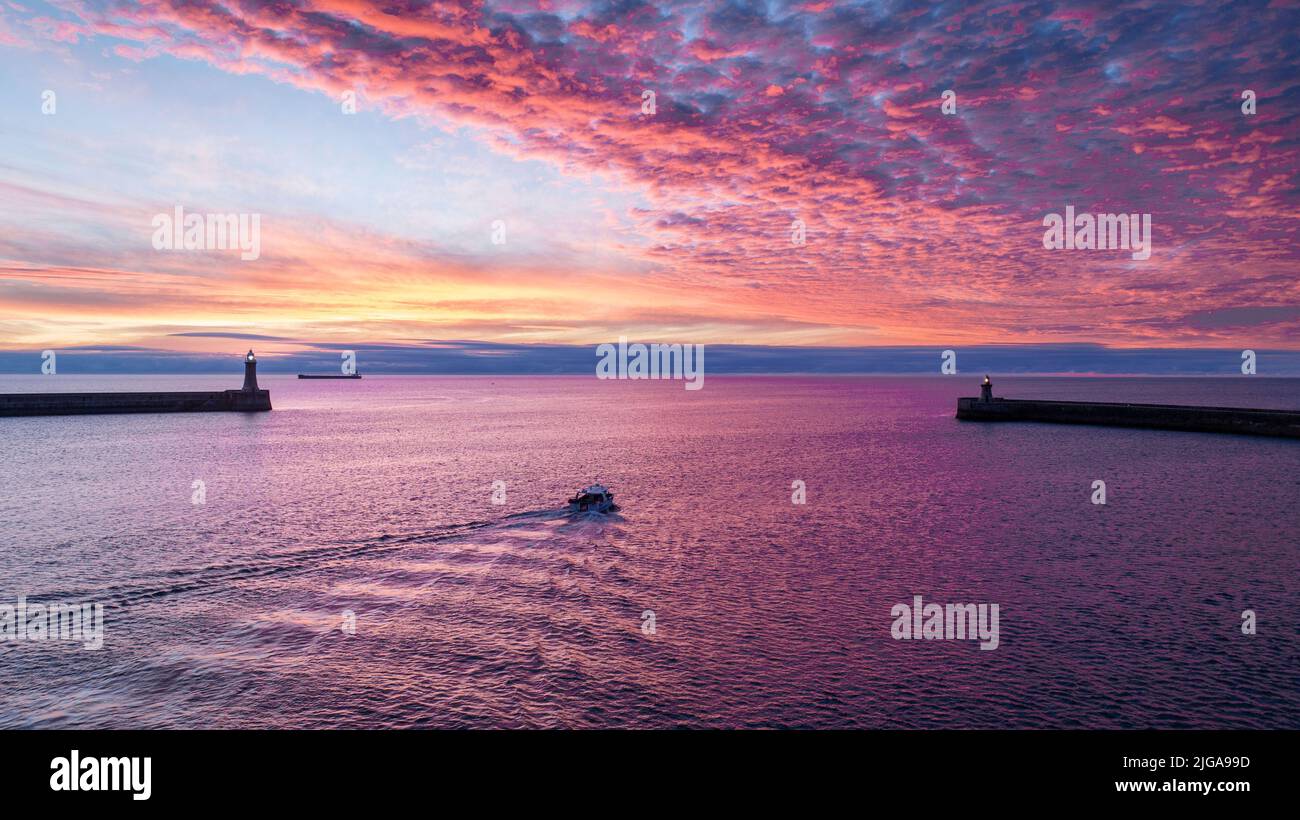 A fishing boat heads out to sea as dawn breaks and the Sun starts to ...