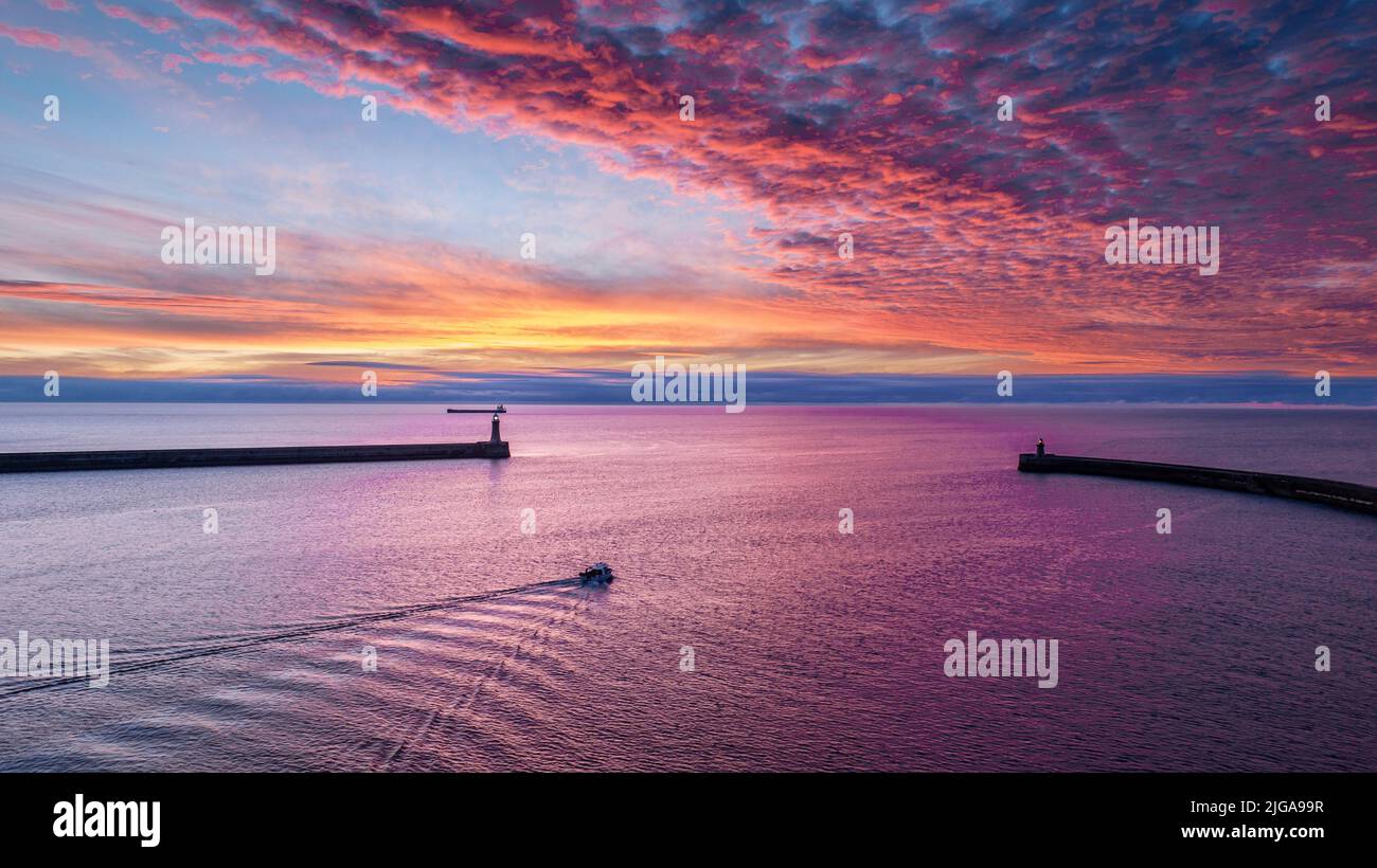 A fishing boat heads out to sea as dawn breaks and the Sun starts to ...