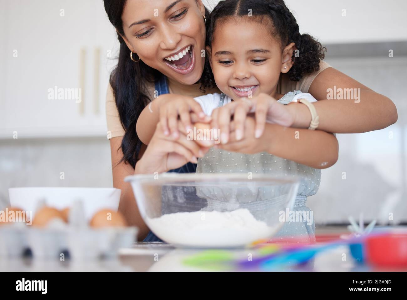 Young mother enjoying baking, bonding with her little daughter in the ...