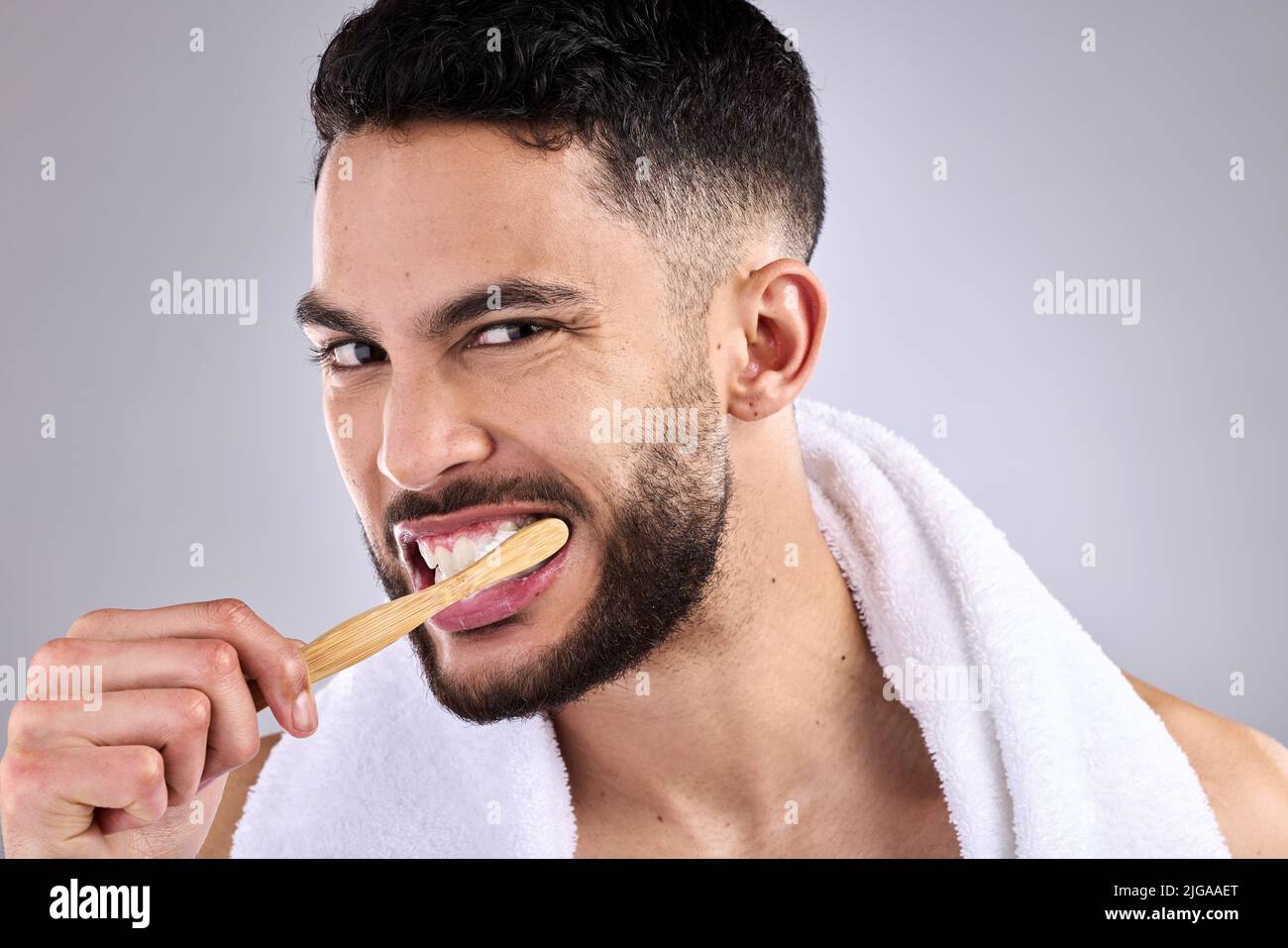 Be gentle but thorough. a young man brushing his teeth while standing ...