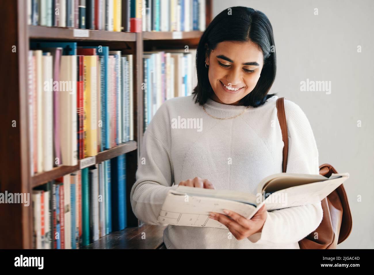 Ready to sink into a new book. a young female student reading a book in ...