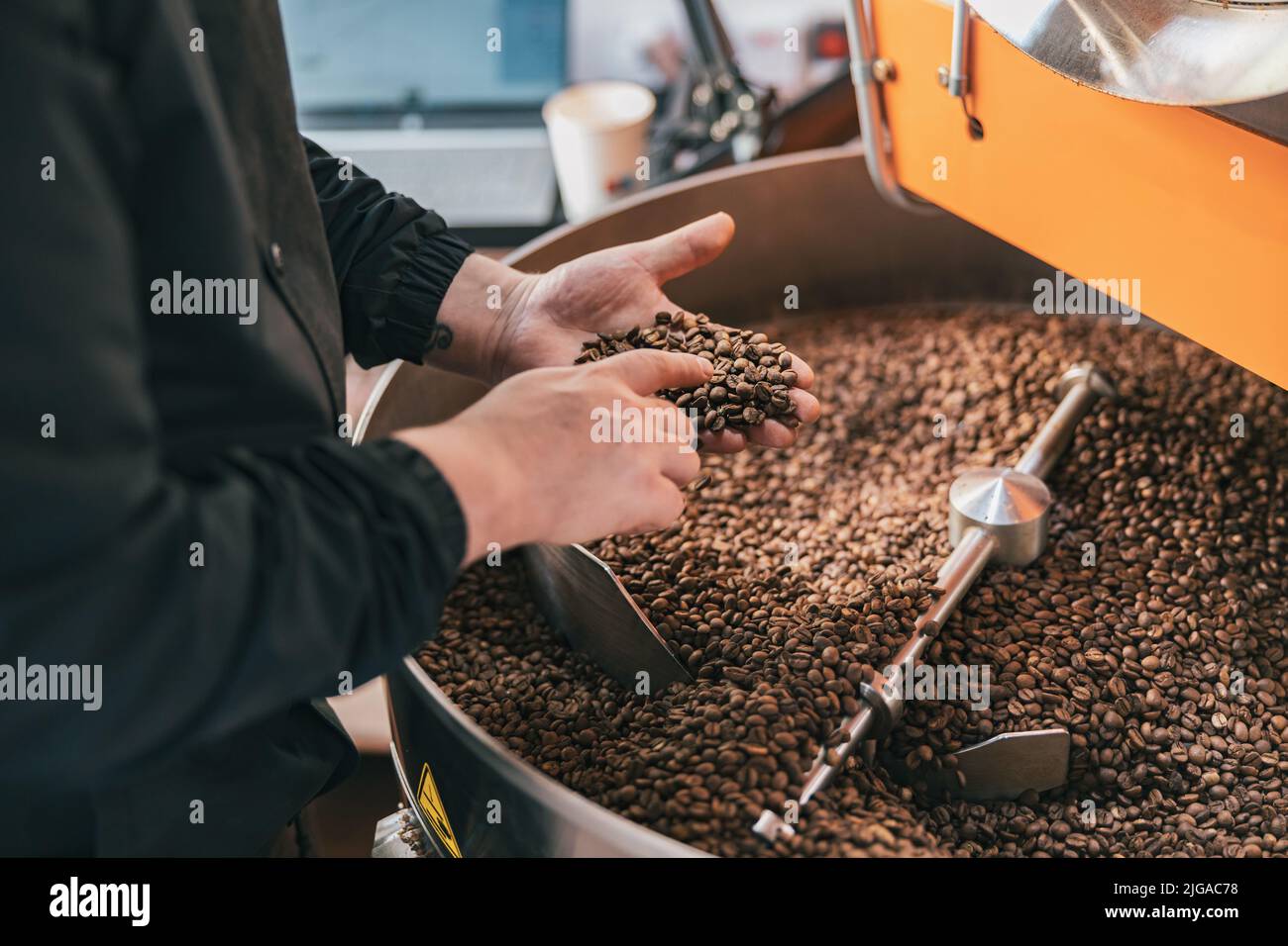 Male barista checks the quality of roasting coffee beans on small ...