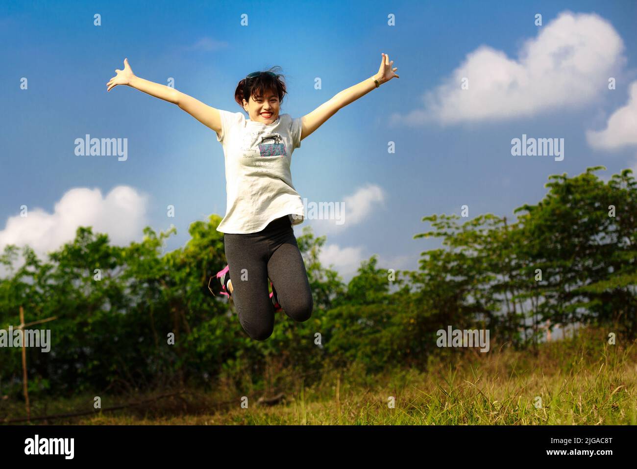 Happy teen girl friends jumping high in blue sky on summer outdoors ...