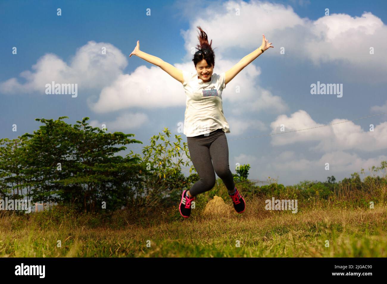 Happy teen girl friends jumping high in blue sky on summer outdoors ...