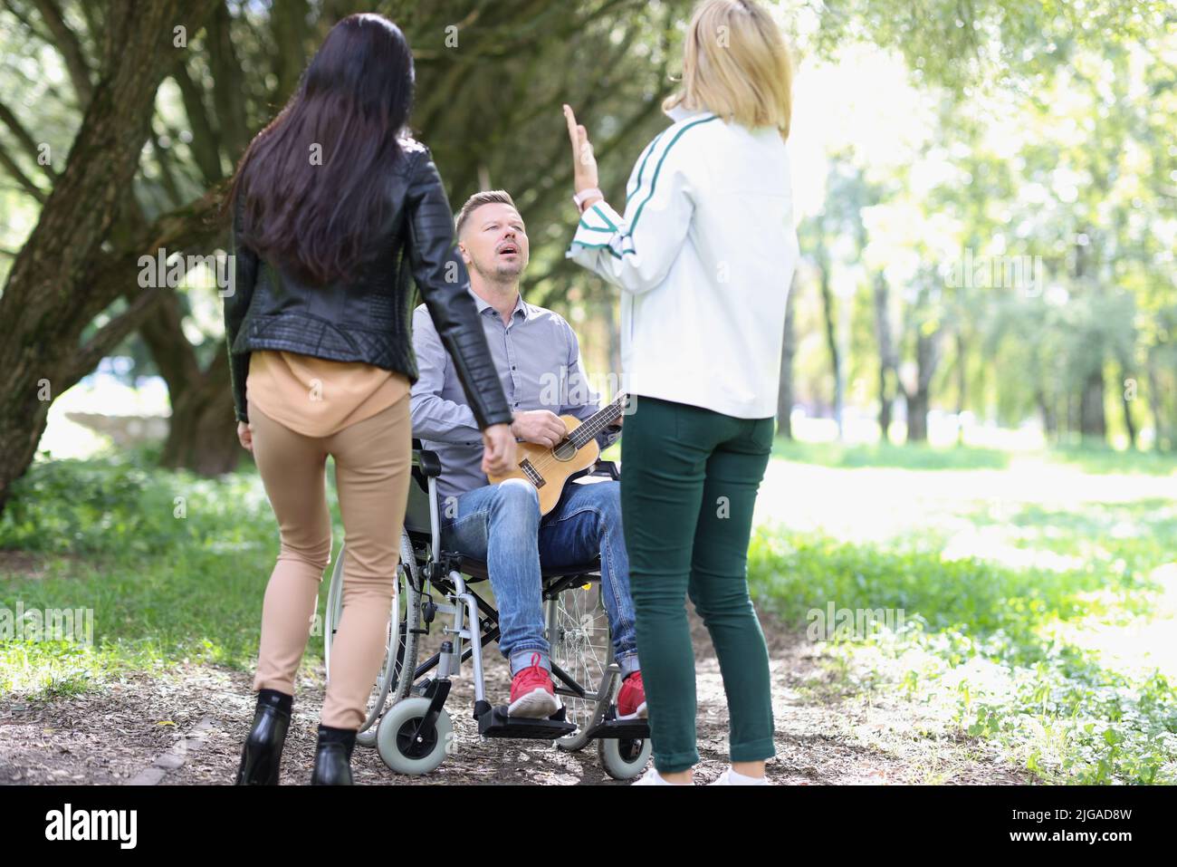Women having fun with disabled man in wheelchair in park Stock Photo ...