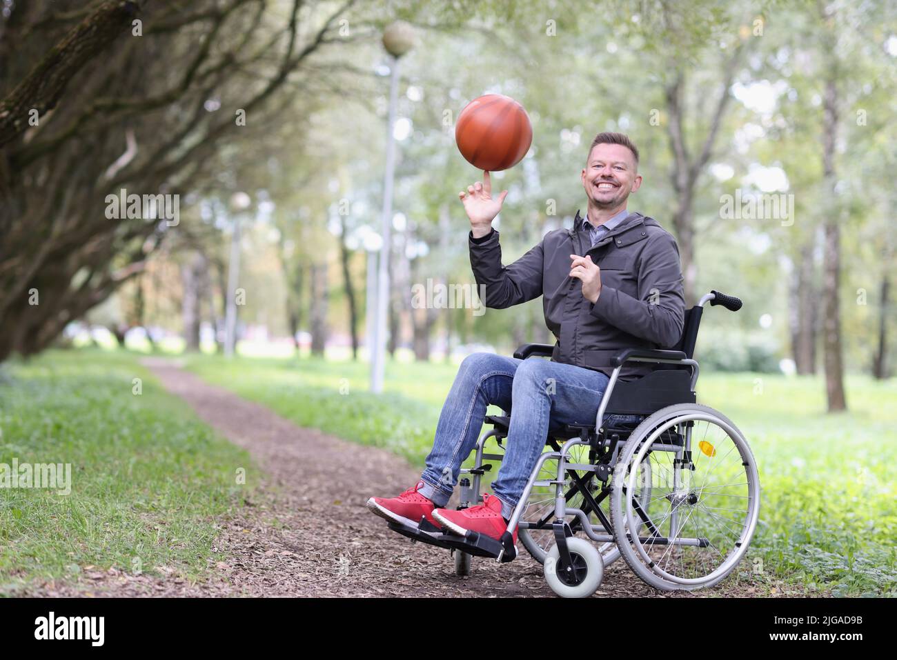 Happy smiling disabled man twirling basketball ball Stock Photo - Alamy