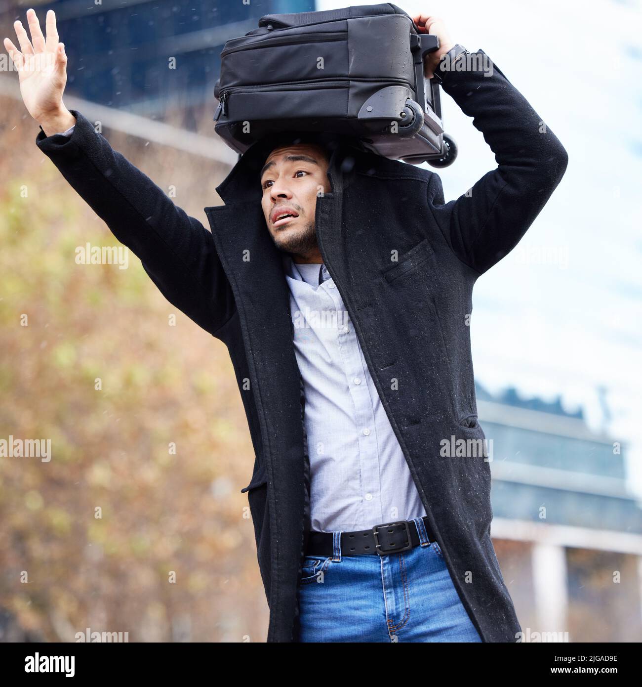 Wait, taxi. a handsome young man hailing a taxi in the rain during his ...