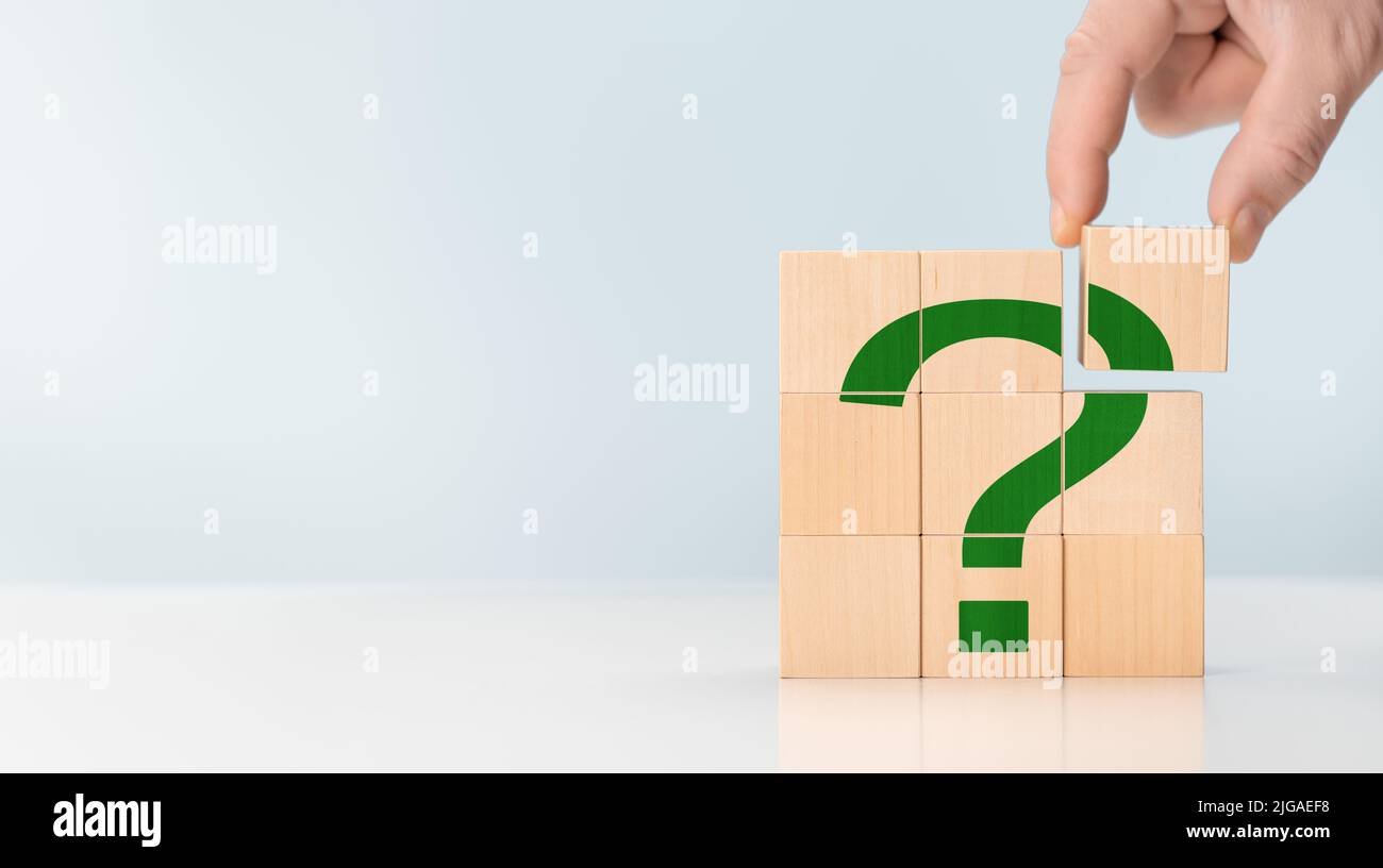 Question marks on Cubes green color, closeup. Space for text. hand hold ...