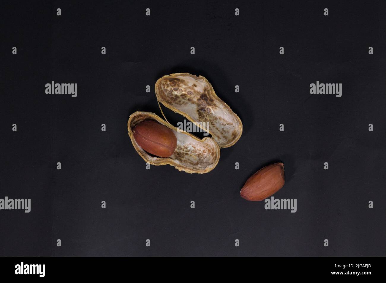 Cracked Shelled peanut with two nuts inside on a black surface Stock ...
