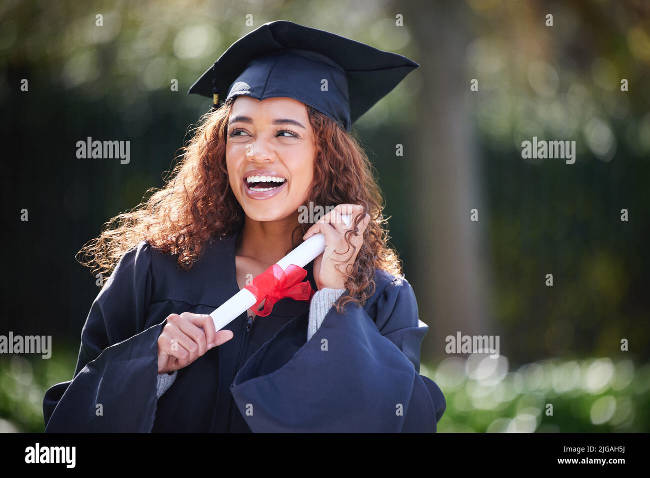 Dreaming about exciting visions of her future. a young woman holding ...